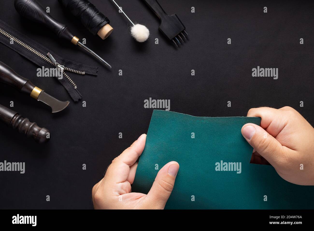 Leather Craftsman holding green leather sample and tool kit for ...