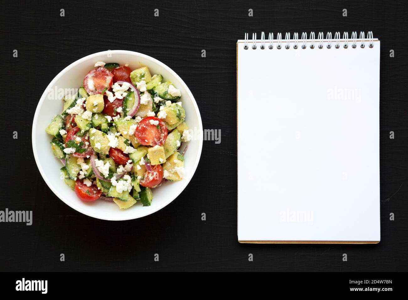 Delicious Avocado Tomato and Cucumber Salad, blank notepad on a black ...