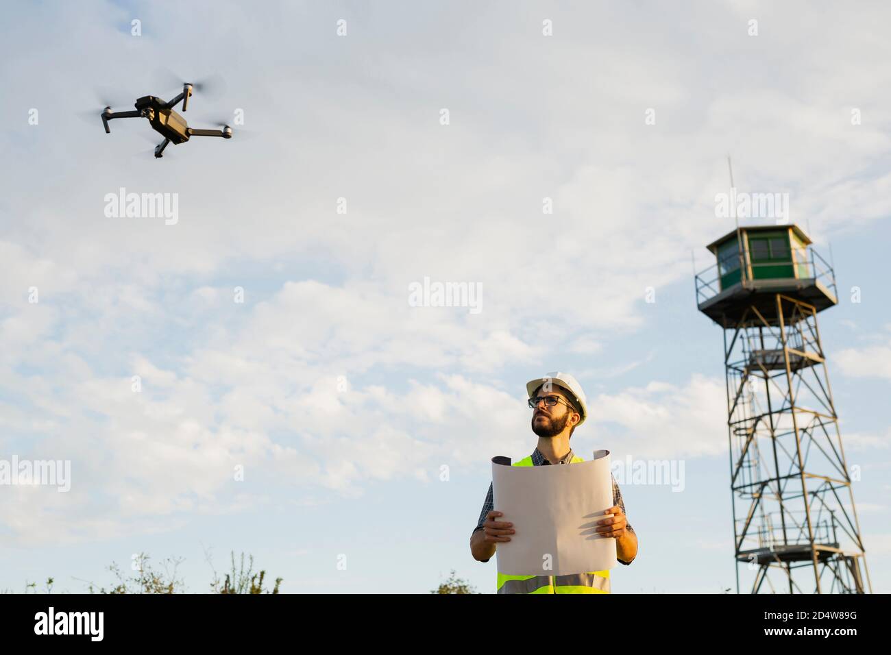 Worker Standing And Checking His Plans next to a flying drone Stock ...