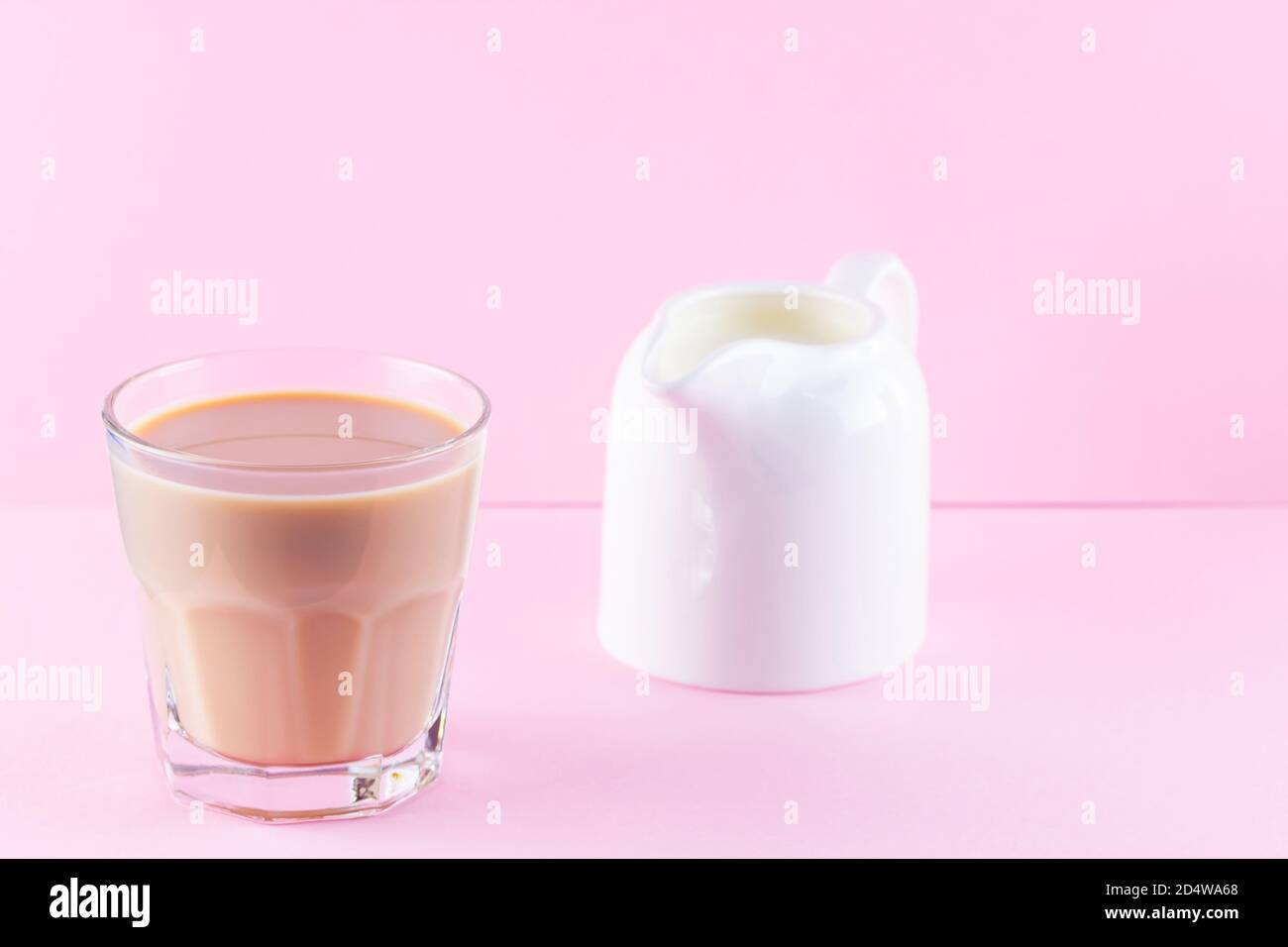 Milk tea on a pink background. Glass of masala chai tea and milk jug ...