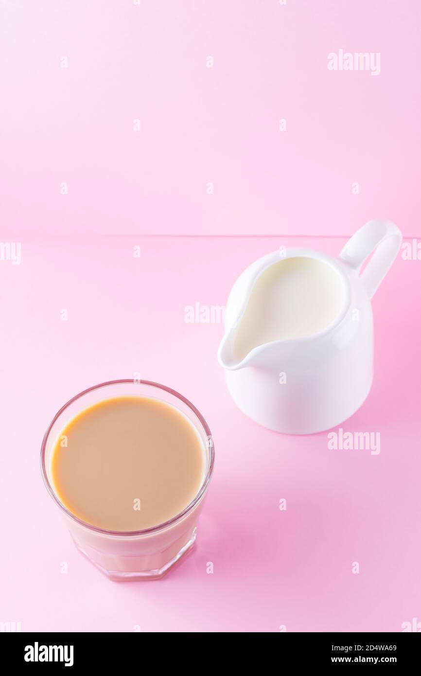 Milk tea on a pink background. Glass of masala chai tea and milk jug ...