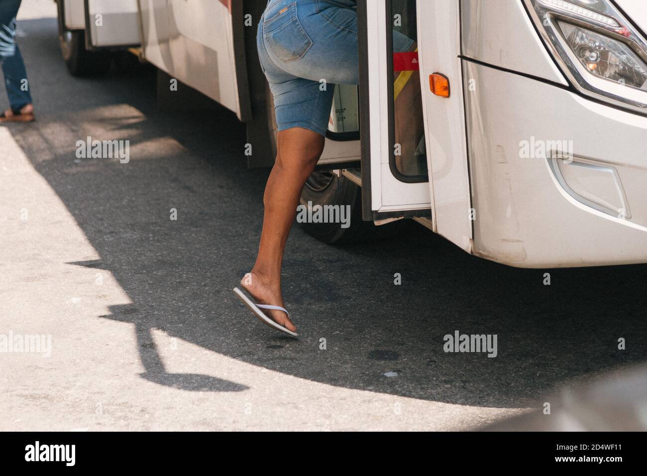 Closeup of a person wearing denim shorts and getting on the bus under ...