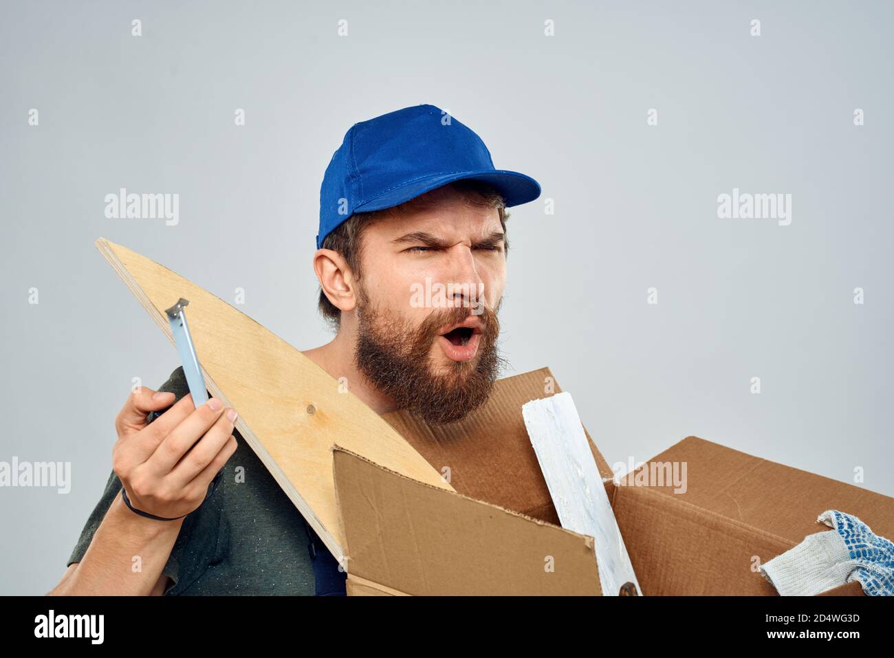 man in work uniform with box in hands tools lifestyle light background ...