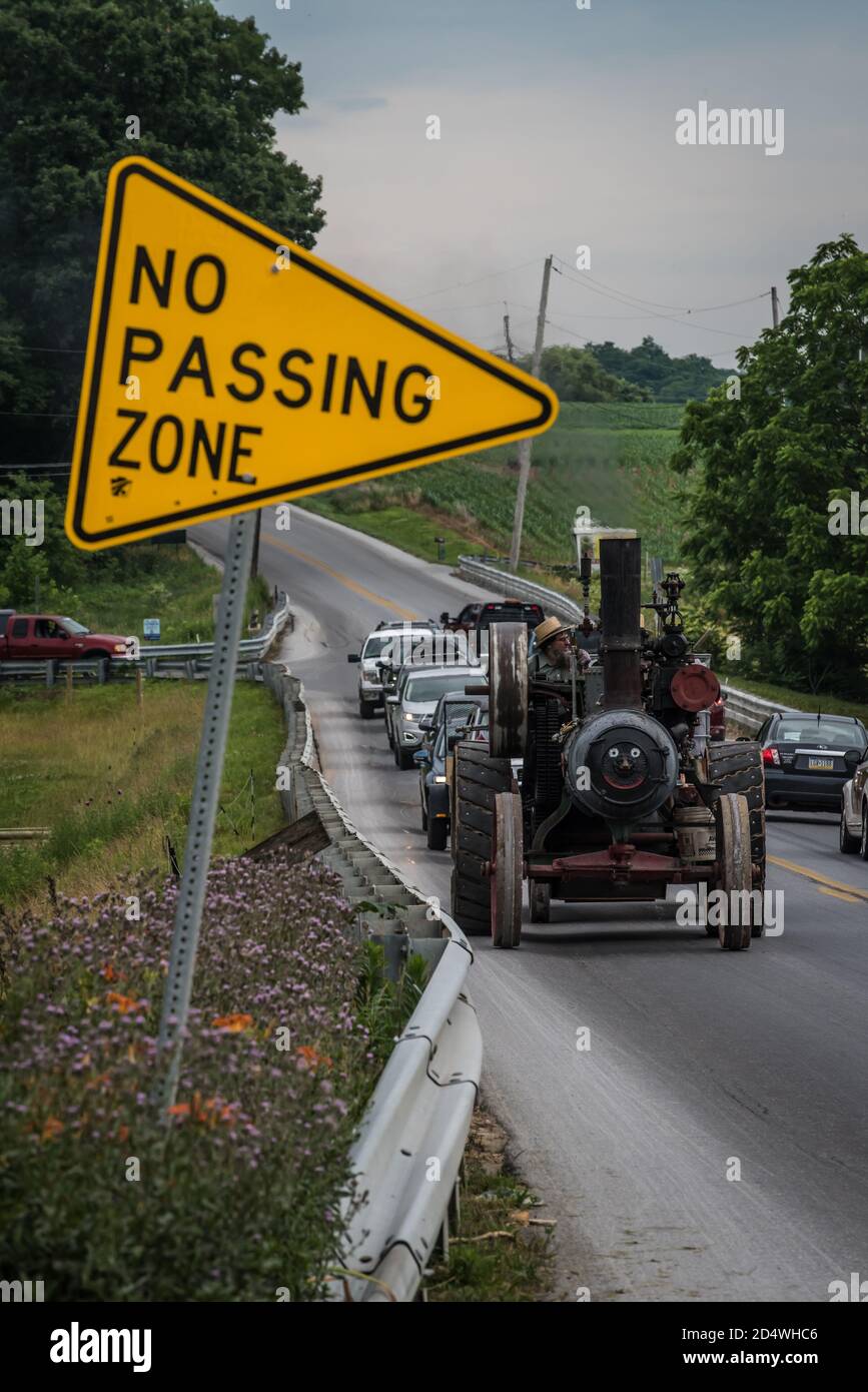 Two amish men slow traffic on no passing zone of highway with steam ...