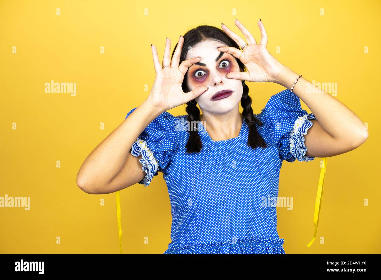 woman wearing a scary doll halloween costume over yellow background ...