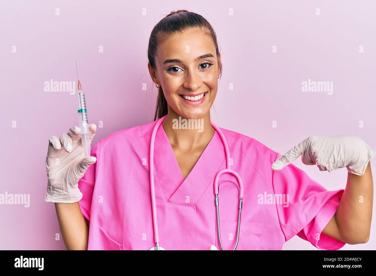 Young hispanic woman wearing doctor stethoscope holding syringe pointing finger to one self ...