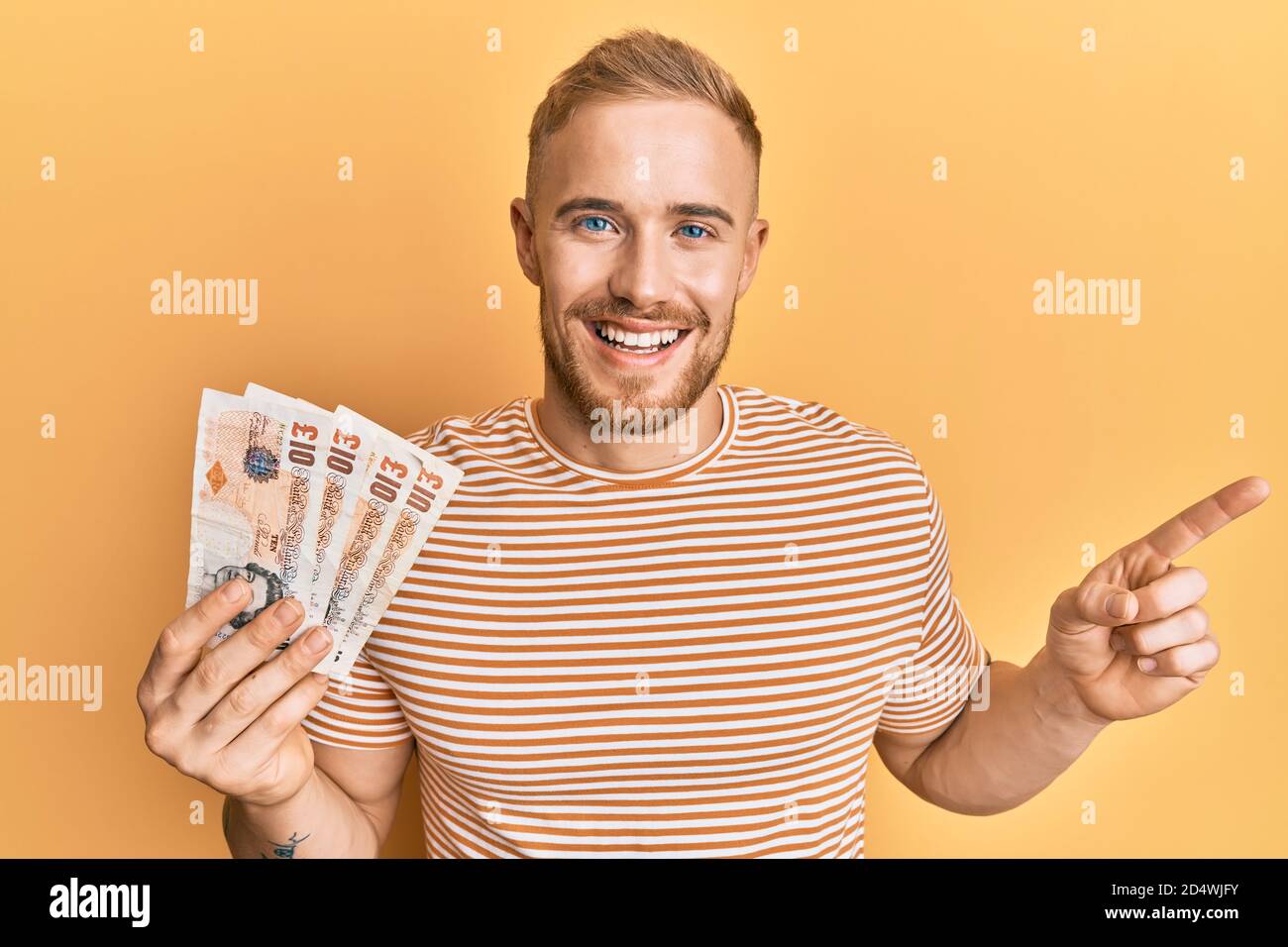 Young caucasian man holding 10 united kingdom pounds banknotes smiling ...