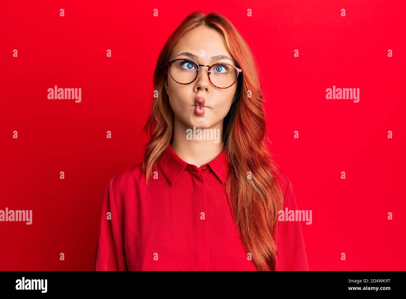 Young beautiful redhead woman wearing casual clothes and glasses over ...