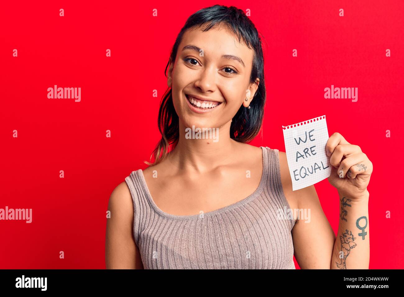 Young woman holding we are equal paper looking positive and happy ...