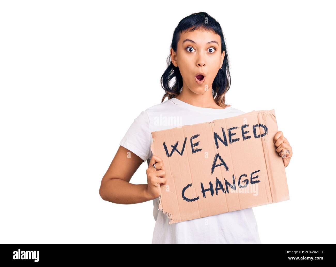 Young woman holding we need a change banner scared and amazed with open ...
