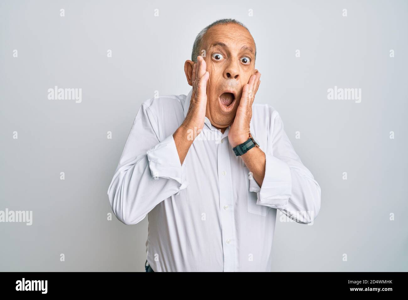 Handsome senior man wearing casual white shirt afraid and shocked ...