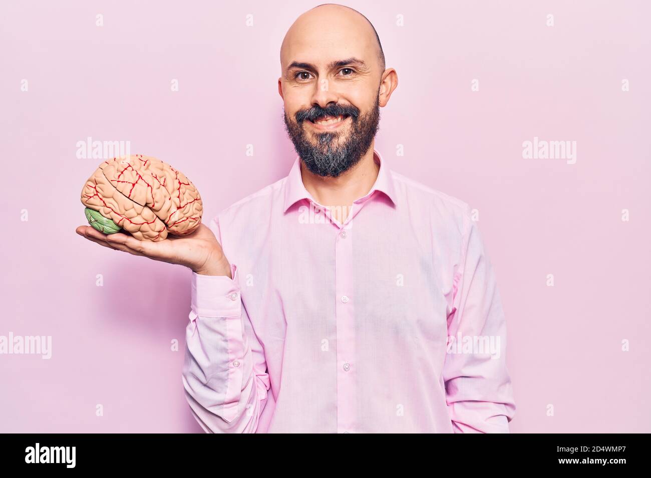 Young handsome man holding brain looking positive and happy standing ...