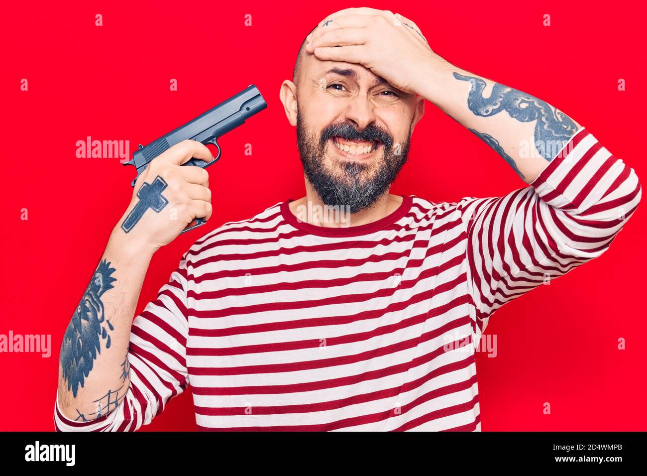 Young handsome man holding gun stressed and frustrated with hand on ...