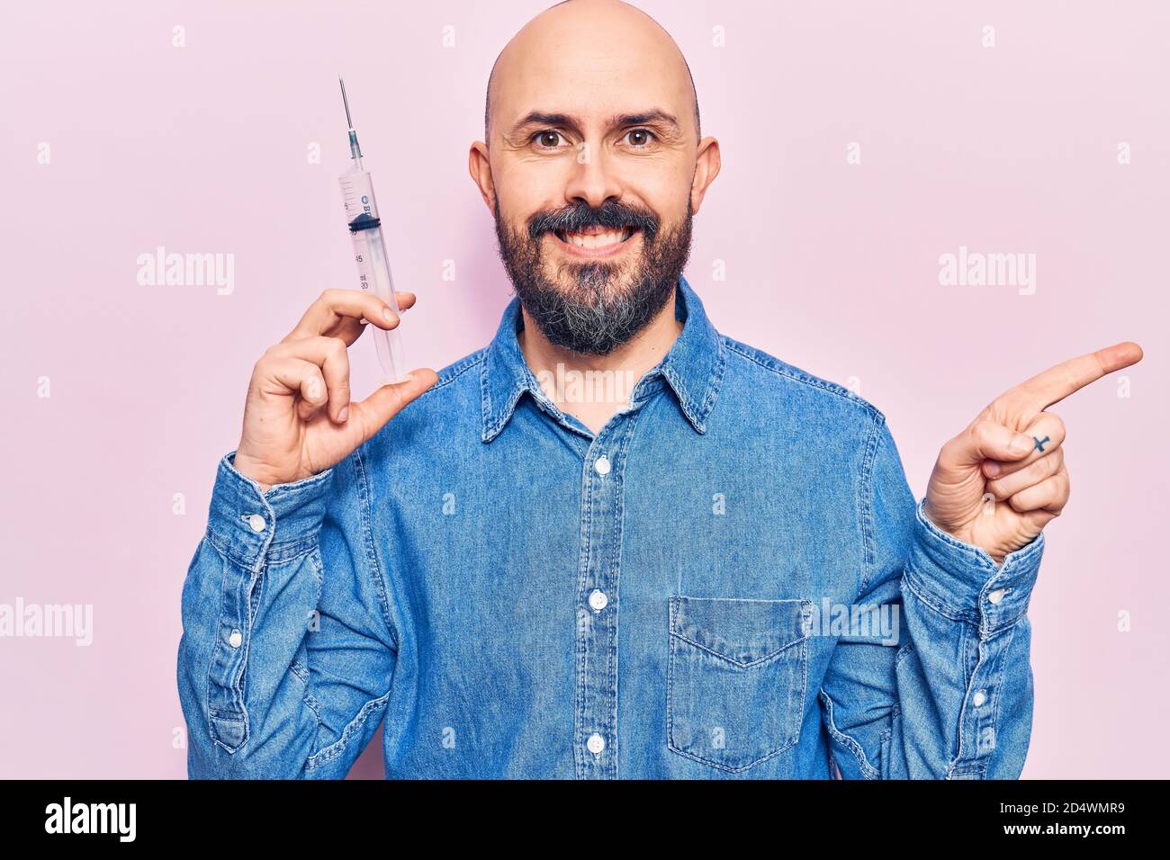 Young handsome man holding syringe smiling happy pointing with hand and finger to the side Stock ...