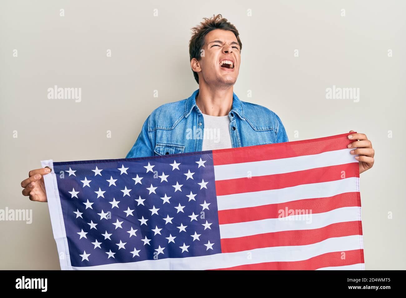 Handsome caucasian man holding united states flag angry and mad ...