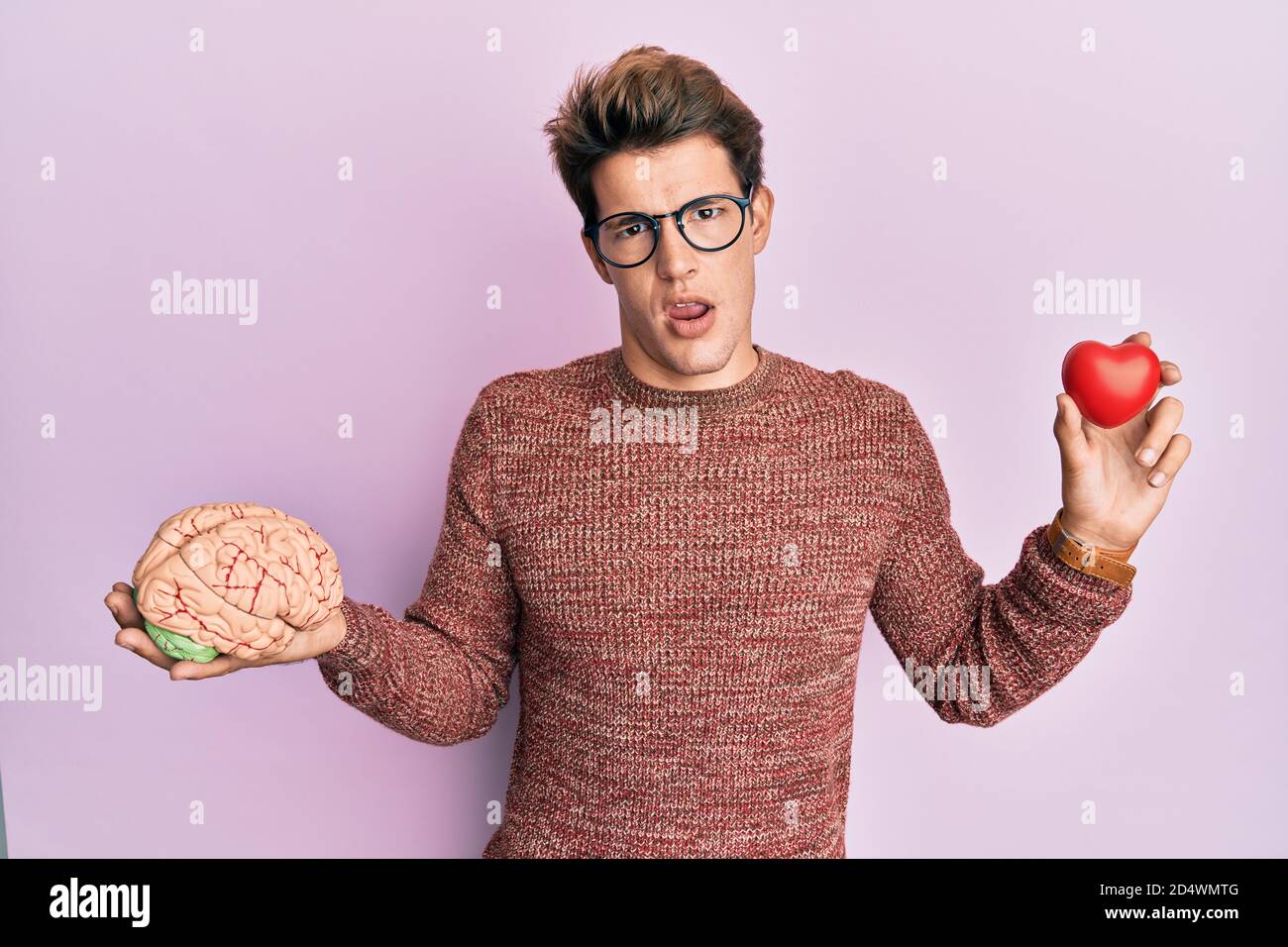 Handsome caucasian man holding brain and heart in shock face, looking ...