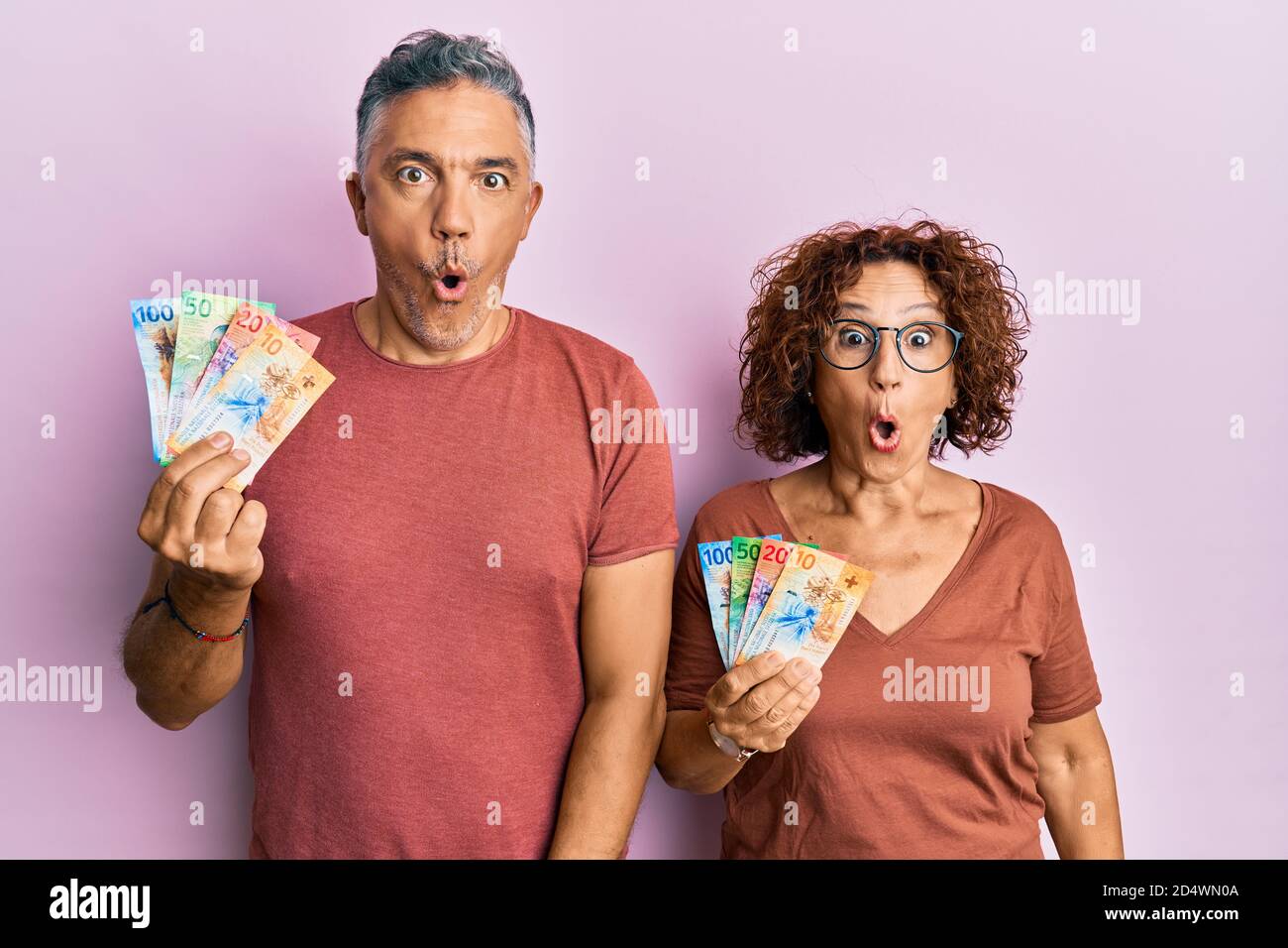 Beautiful middle age couple together holding swiss franc banknotes ...