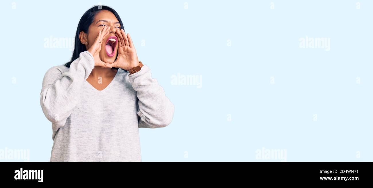 Hispanic woman with long hair wearing casual clothes shouting angry out ...