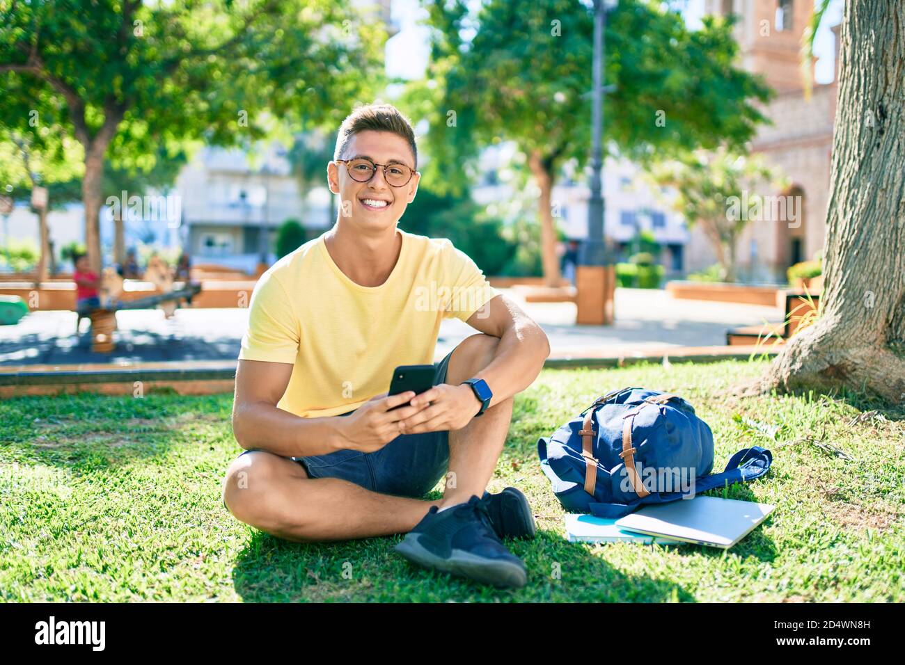 Young hispanic student smiling happy using smartphone sitting on the ...