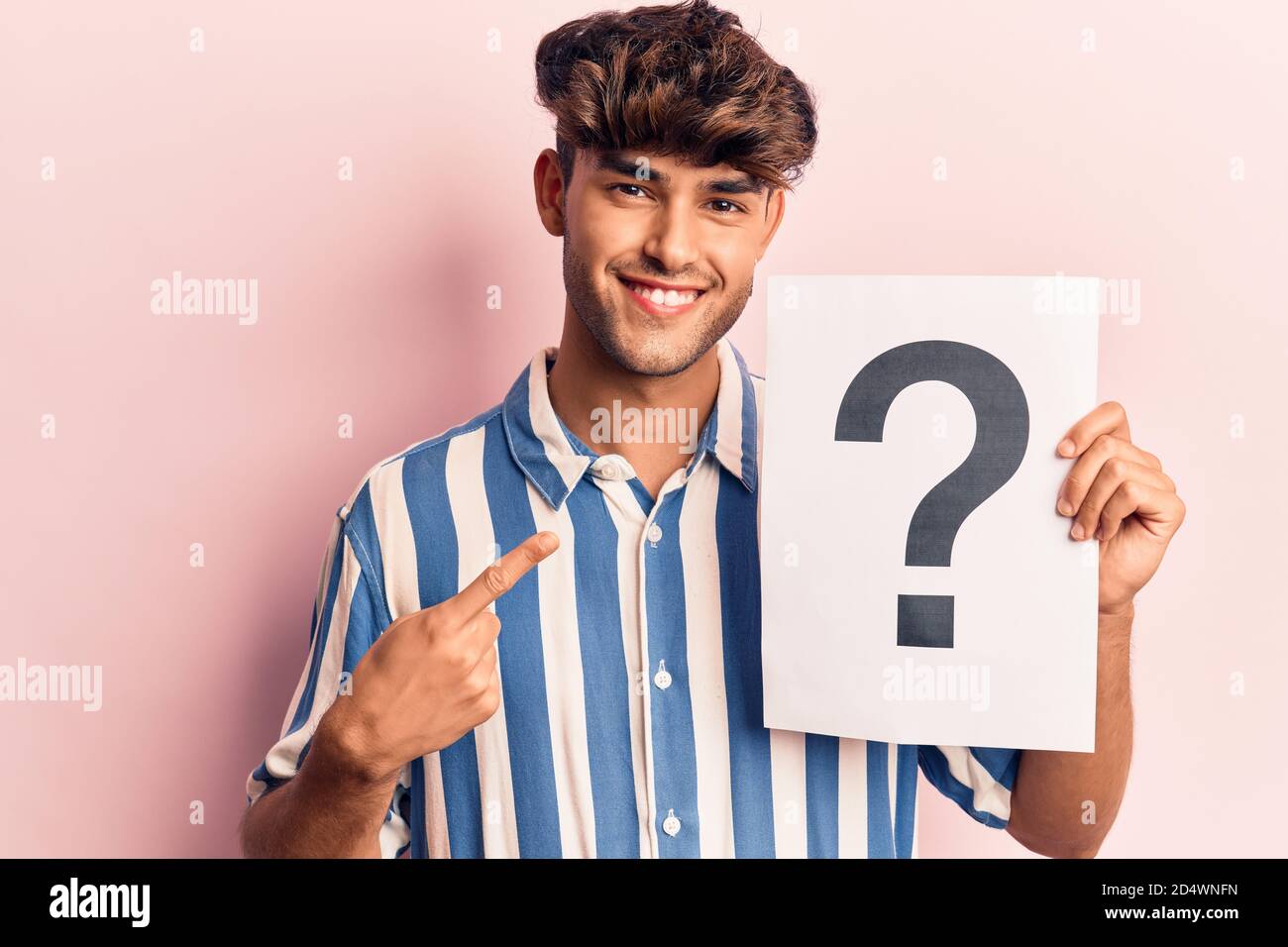 Young hispanic man holding question mark smiling happy pointing with ...