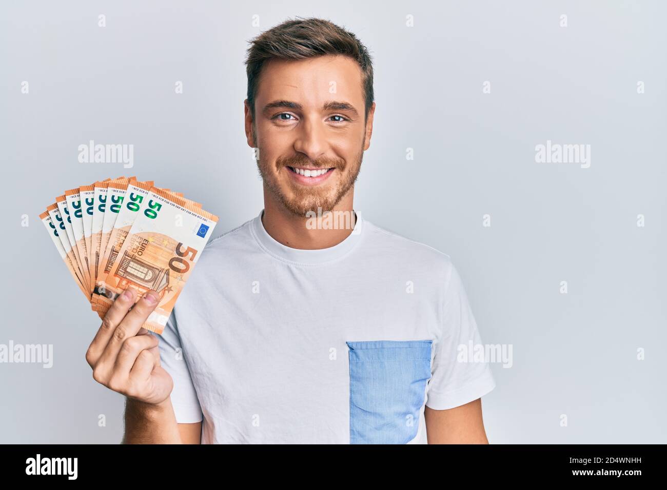 Handsome caucasian man holding 50 euro banknotes looking positive and ...