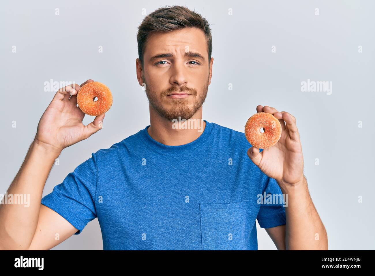 Handsome caucasian man eating donuts depressed and worry for distress ...