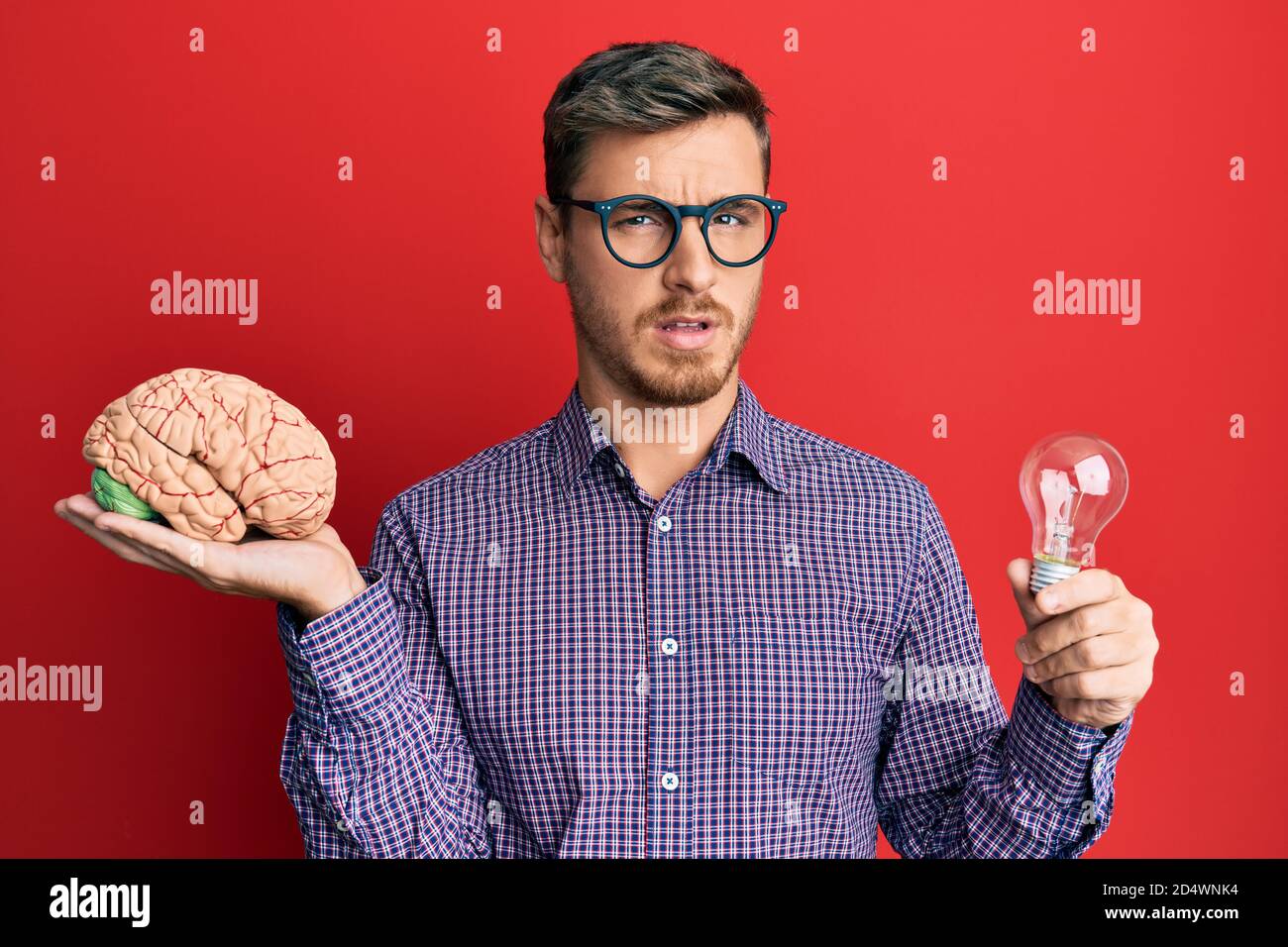 Handsome caucasian man holding brain and lightbulb for inspiration and ...