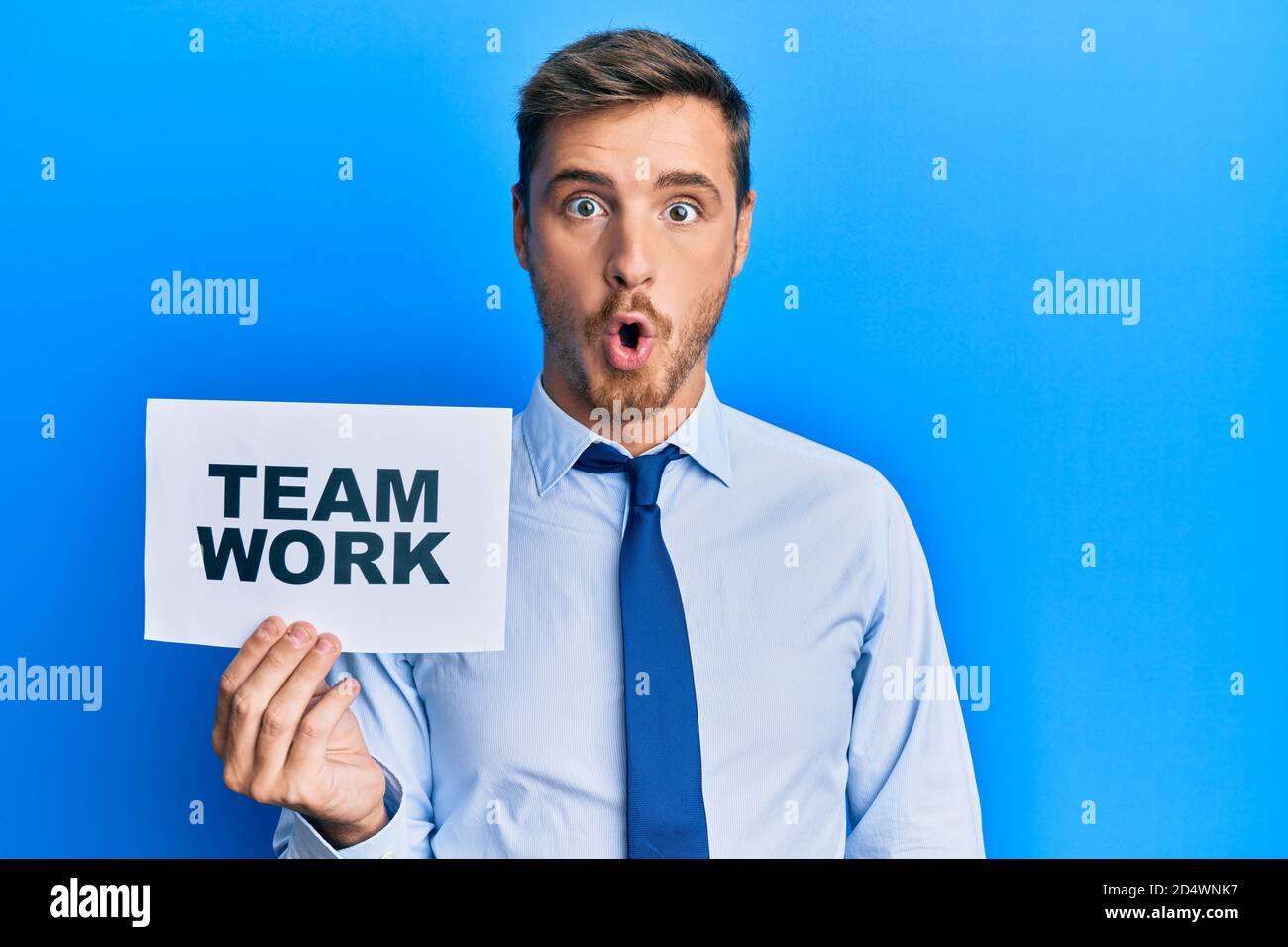 Handsome caucasian business man holding team work banner scared and ...