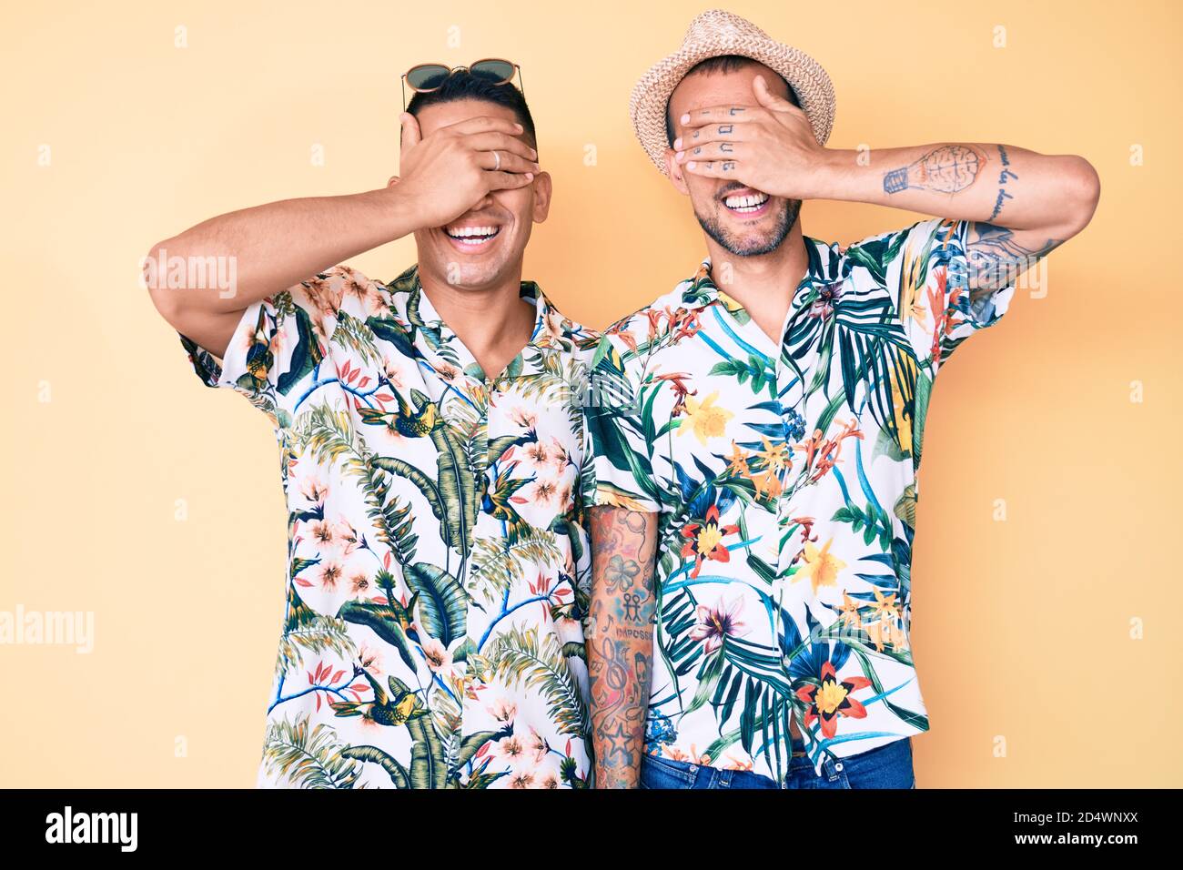 Young gay couple of two men wearing summer hat and hawaiian shirt ...