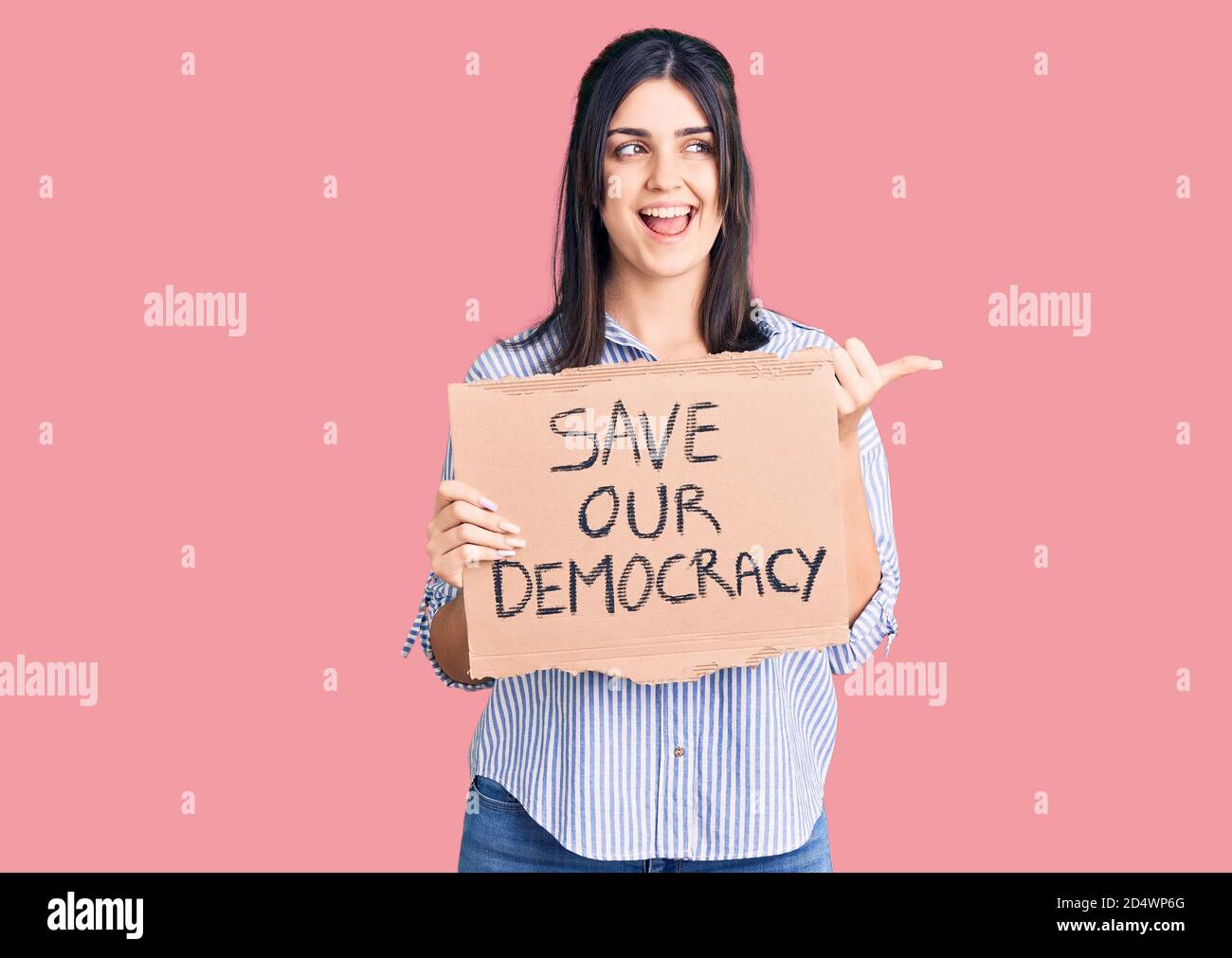 Young beautiful girl holding save our democracy cardboard banner ...