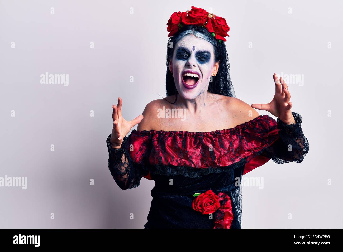 Young woman wearing mexican day of the dead makeup shouting frustrated ...