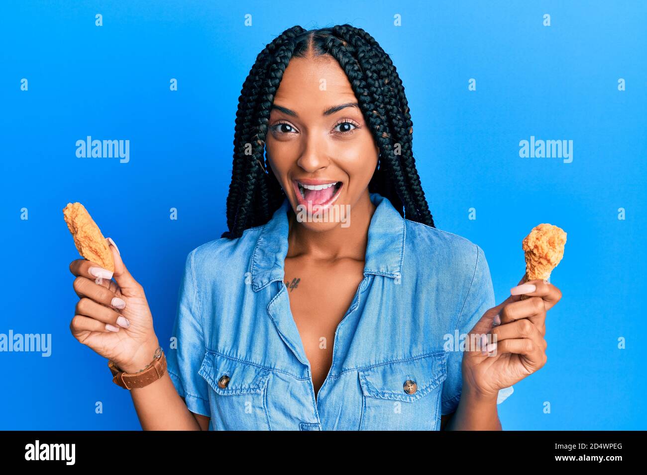 Beautiful hispanic woman eating chicken wings celebrating crazy and ...
