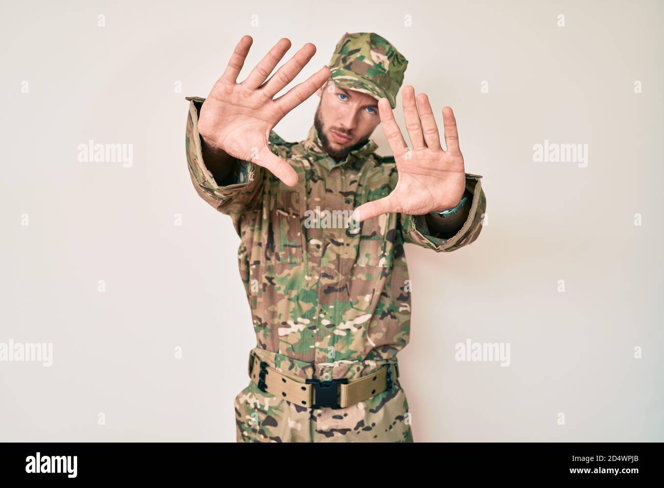 Young caucasian man wearing camouflage army uniform doing frame using ...