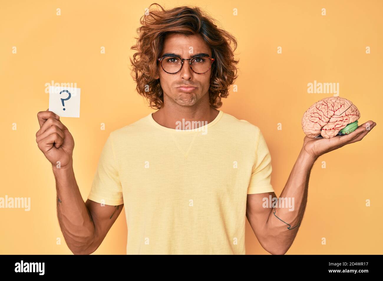 Young hispanic man holding brain and question mark depressed and worry ...