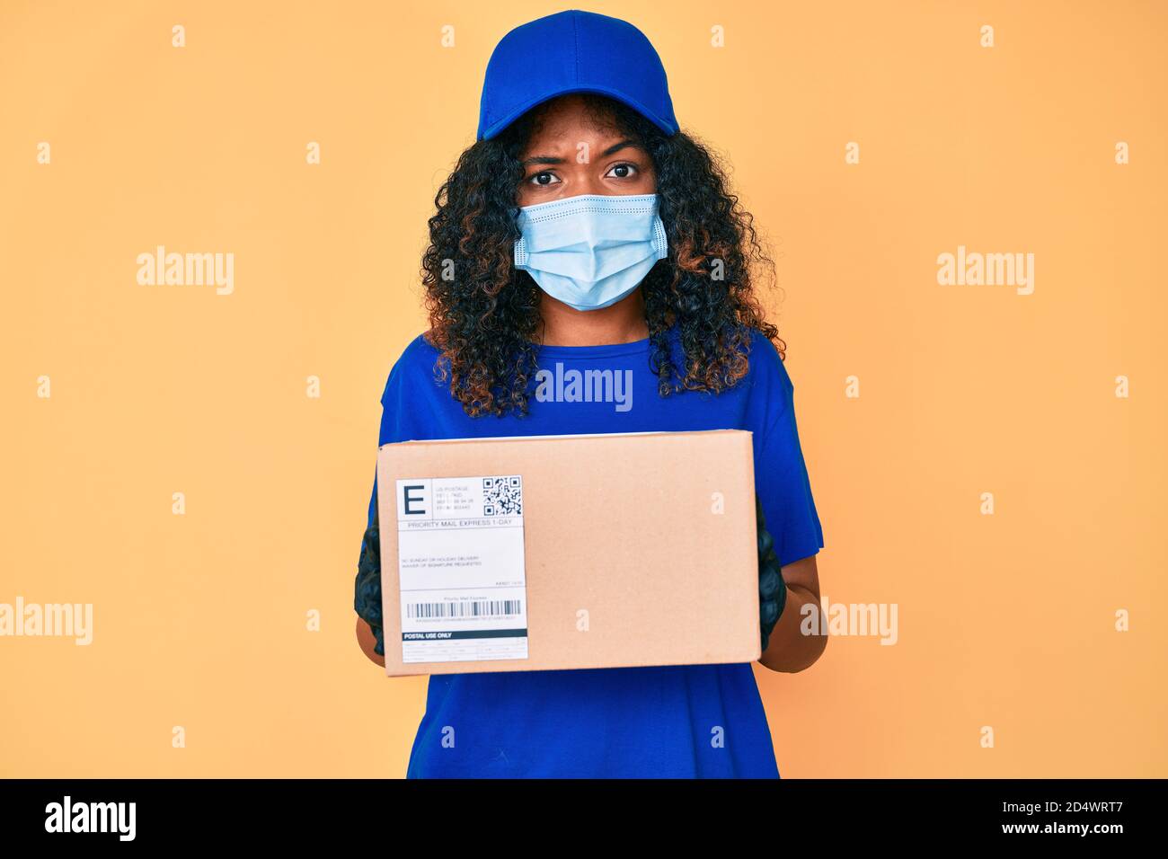 Young african american woman wearing medical mask holding delivery ...