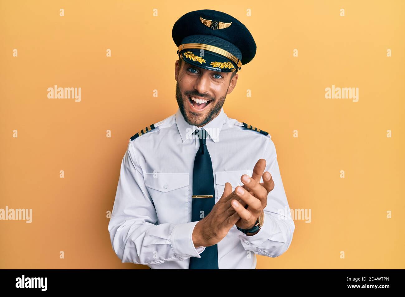 Handsome hispanic man wearing airplane pilot uniform clapping and ...