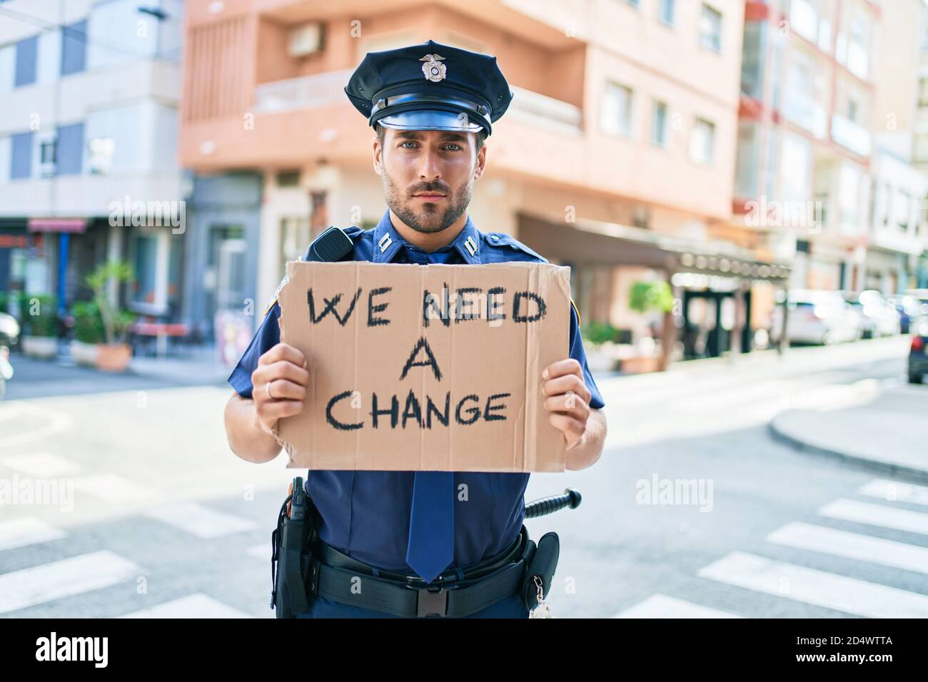 Young handsome hispanic policeman wearing police uniform with serious ...