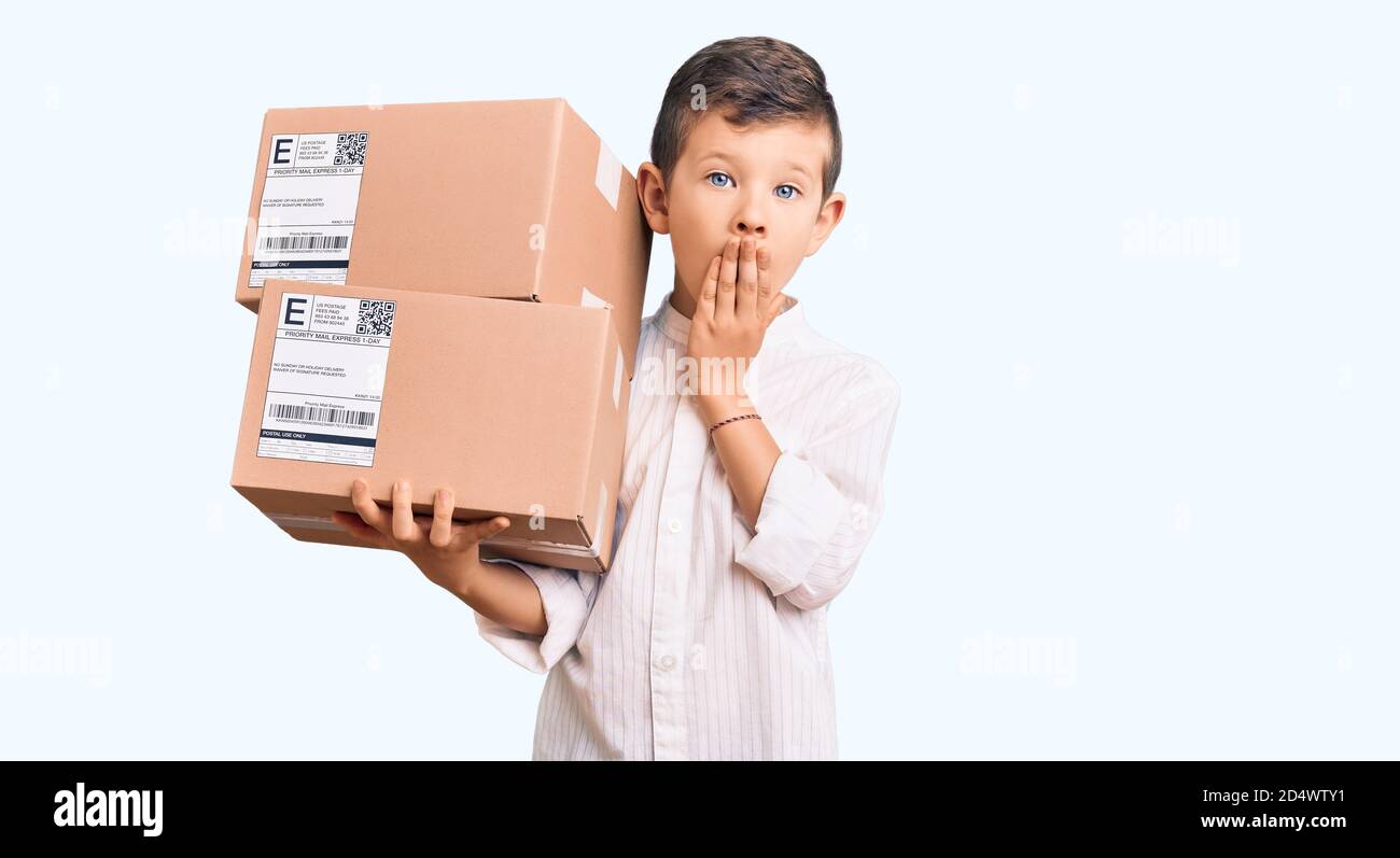 Cute blond kid holding delivery package covering mouth with hand ...