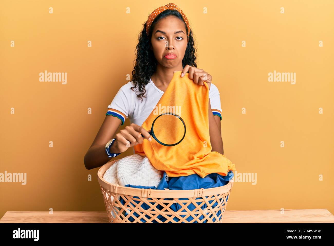 Young african american girl holding magnifying glass looking for stain ...