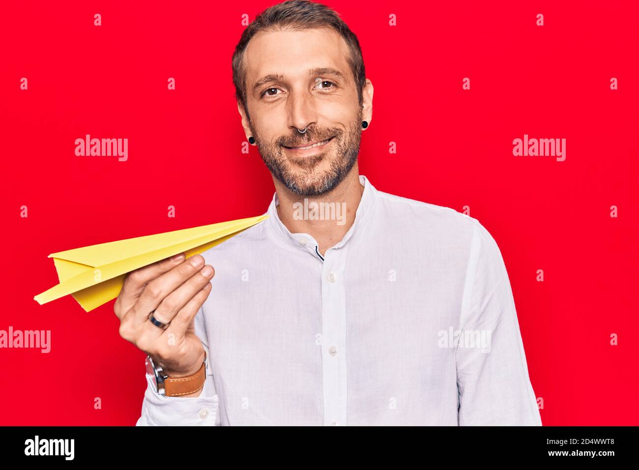Young handsome man holding paper airplane looking positive and happy ...