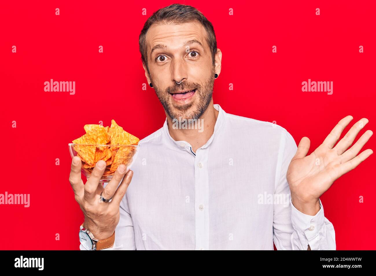 Young handsome man holding nachos potato chips celebrating achievement ...