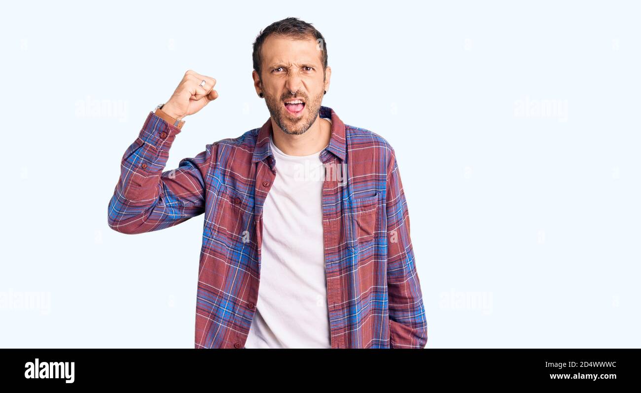 Young handsome man wearing casual clothes angry and mad raising fist ...