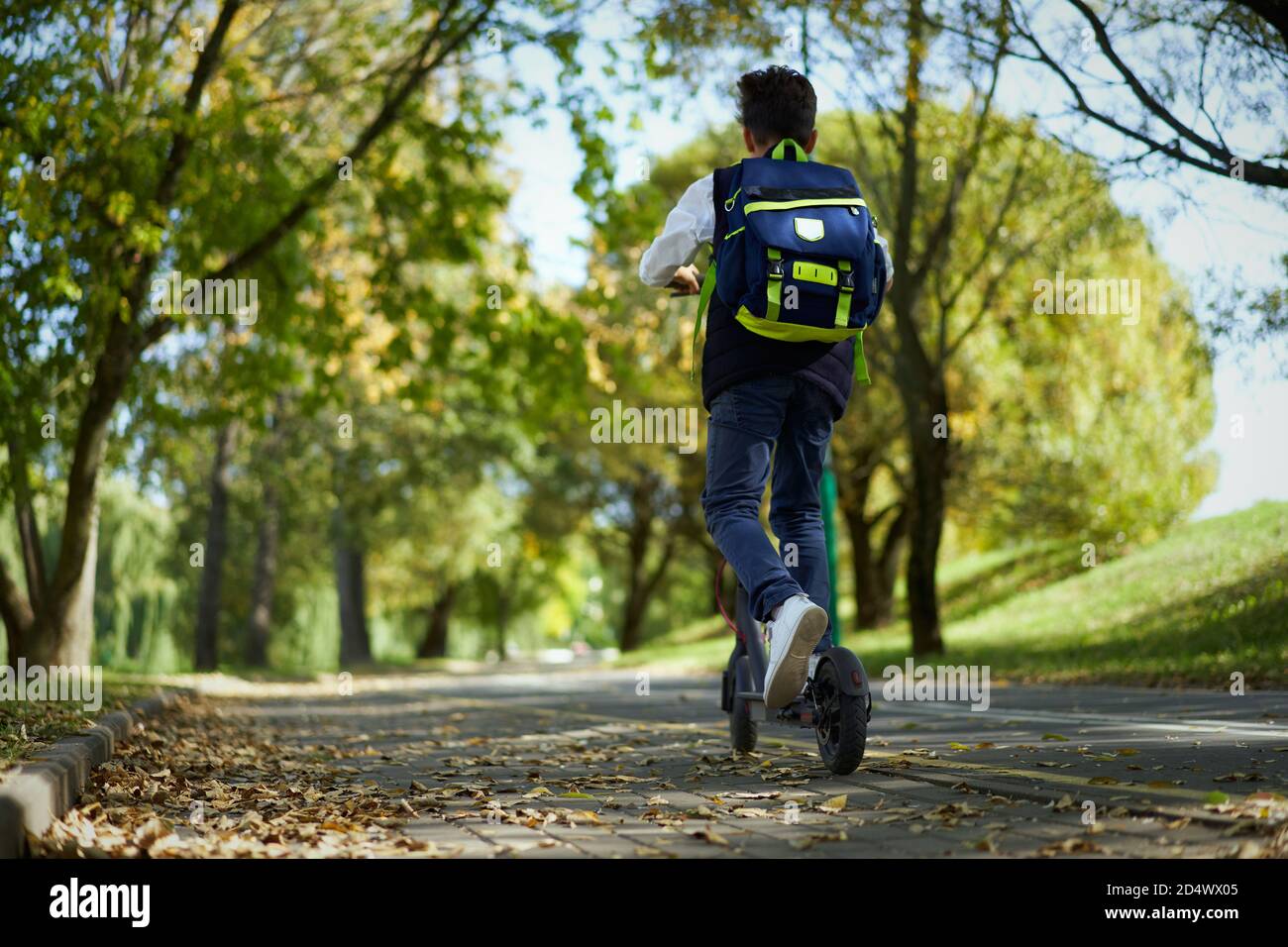 Schoolboy with backpack riding on electric scooter to school Stock ...