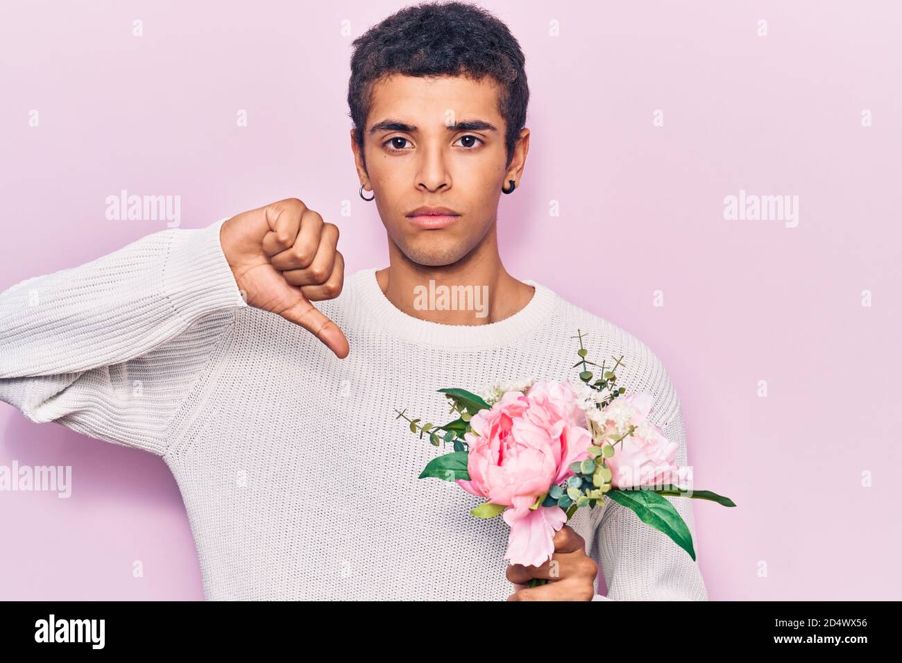 Young african amercian man holding flowers with angry face, negative ...