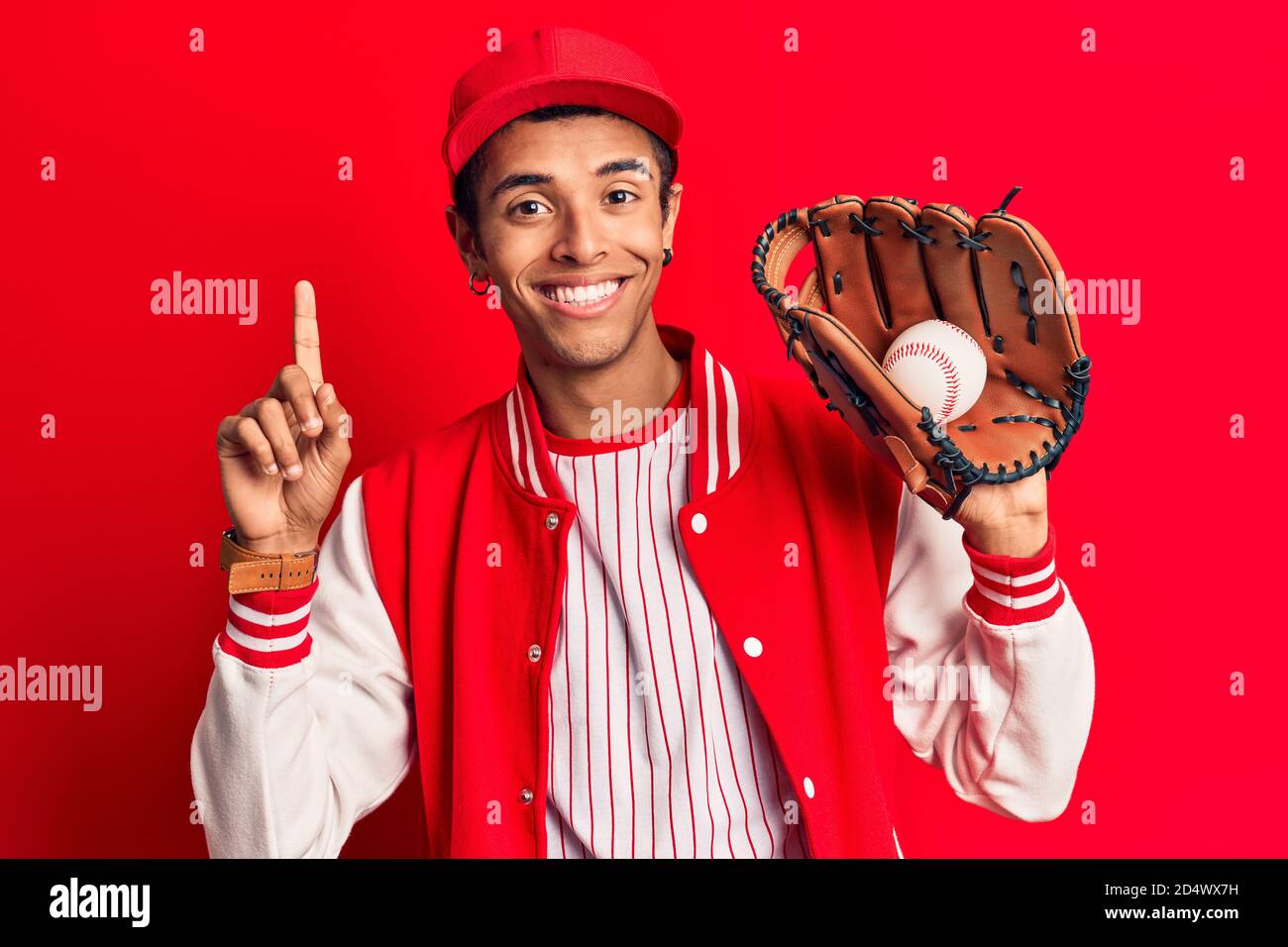 Young african amercian man wearing baseball uniform holding golve and ...