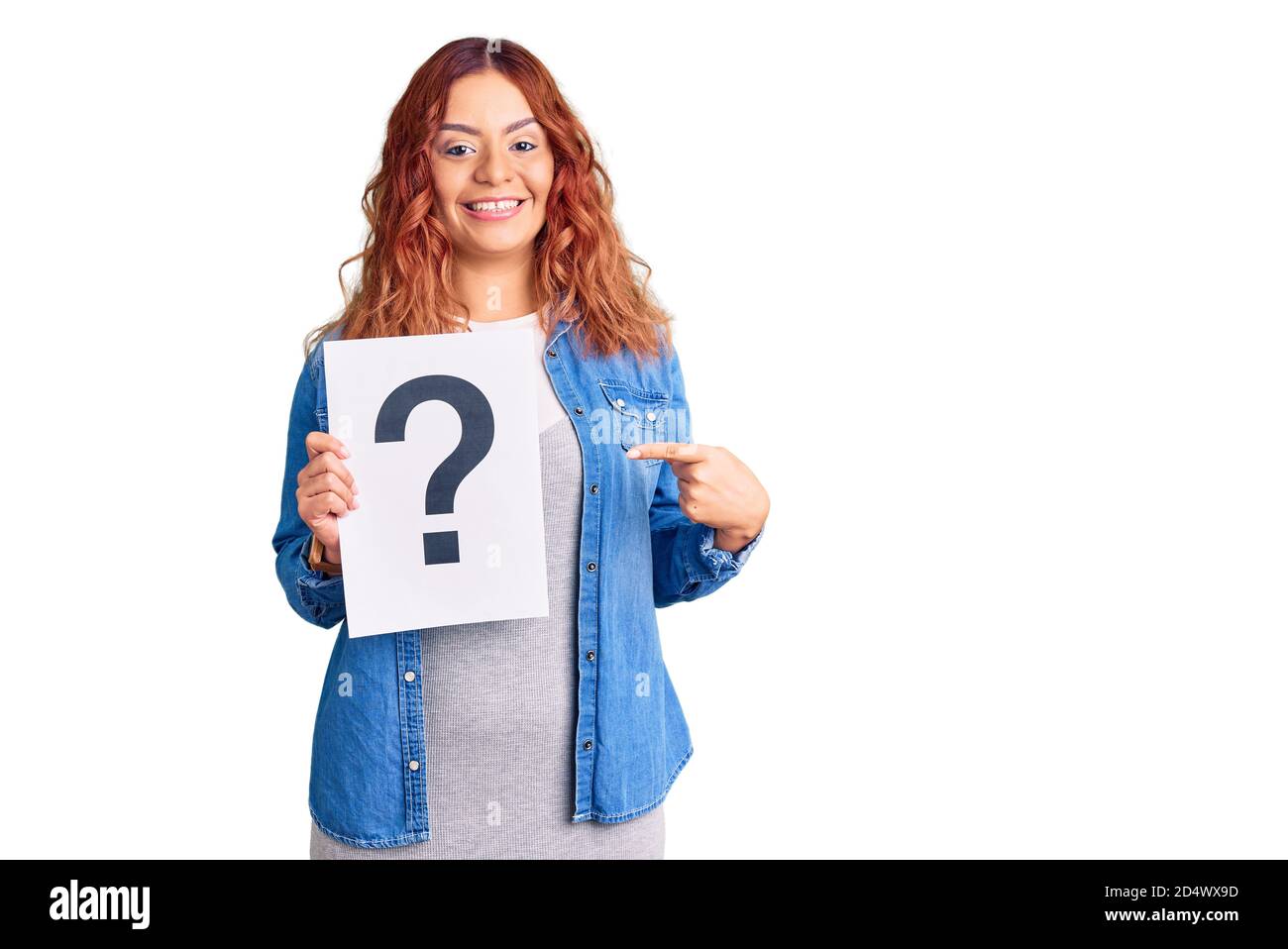Young latin woman holding question mark smiling happy pointing with ...
