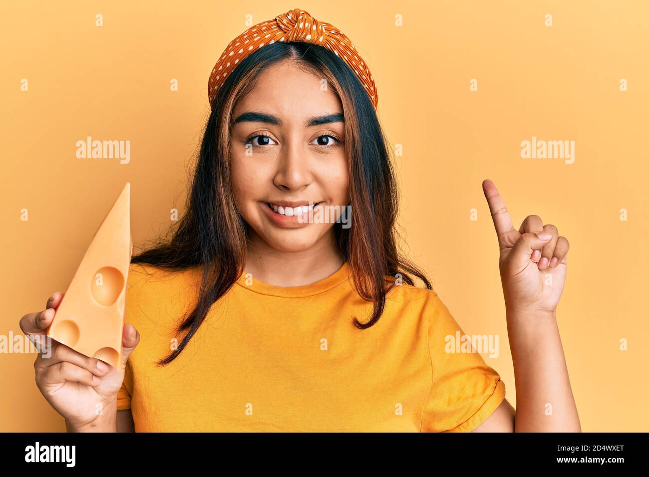Young latin woman eating emmental cheese smiling with an idea or ...