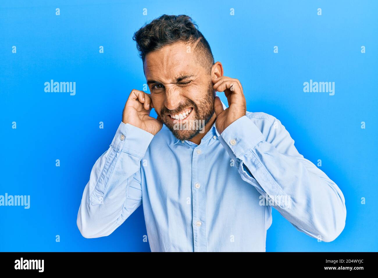 Handsome man with beard wearing casual clothes covering ears with ...