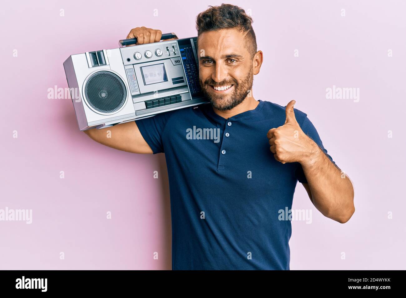 Handsome man with beard holding boombox, listening to music smiling ...