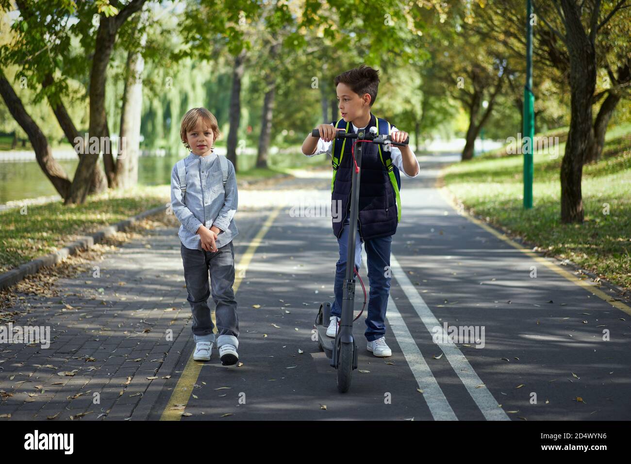 Schoolboy with backpack riding on electric scooter to school Stock ...